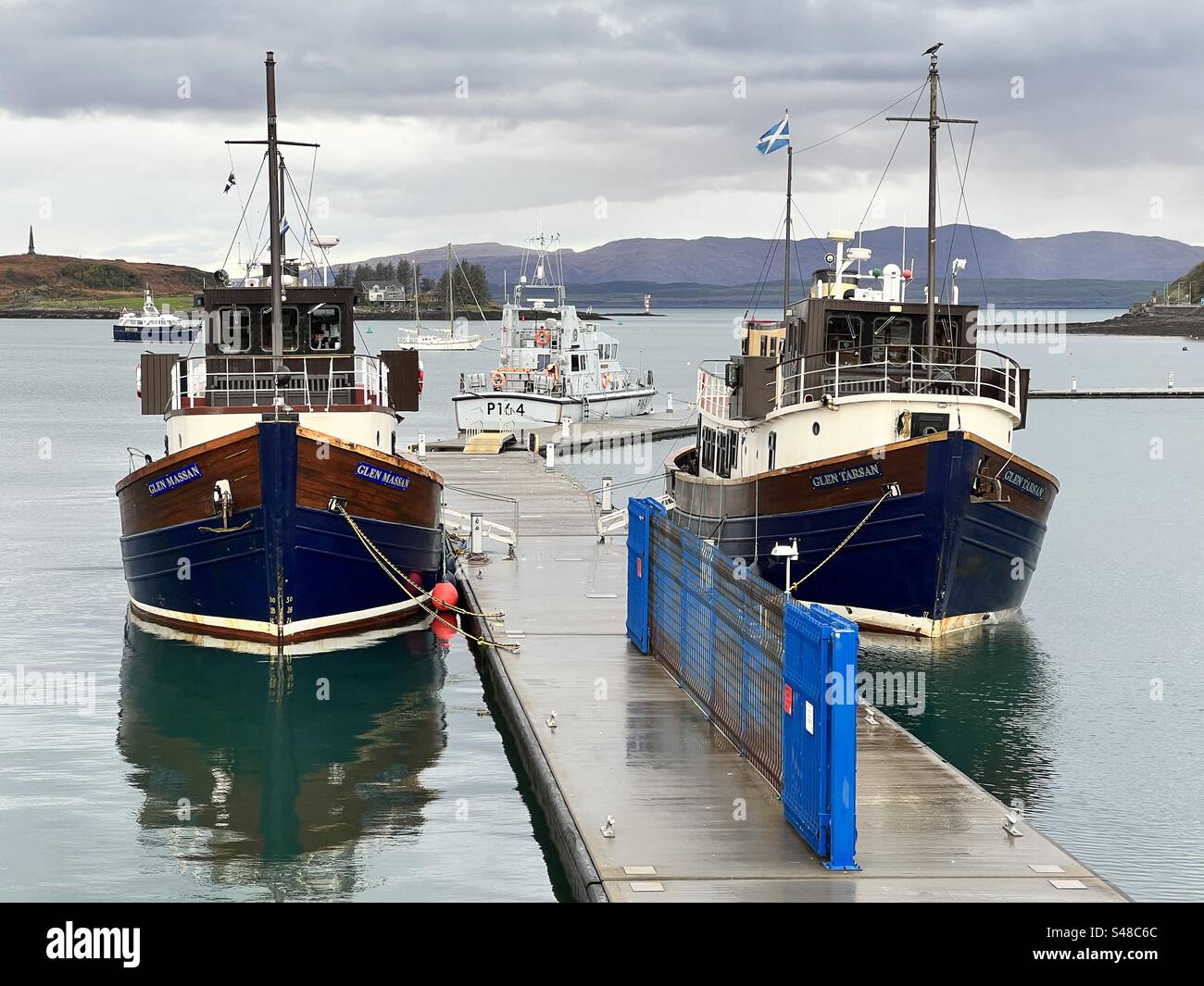 Two nearly identical old-type blue motor boat moored by a pontoon in ...