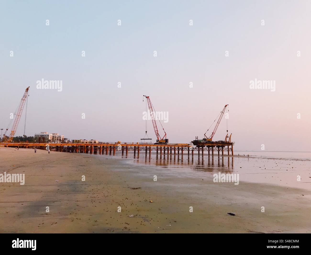 Construction crane and infrastructure on a beach during sunset Stock ...