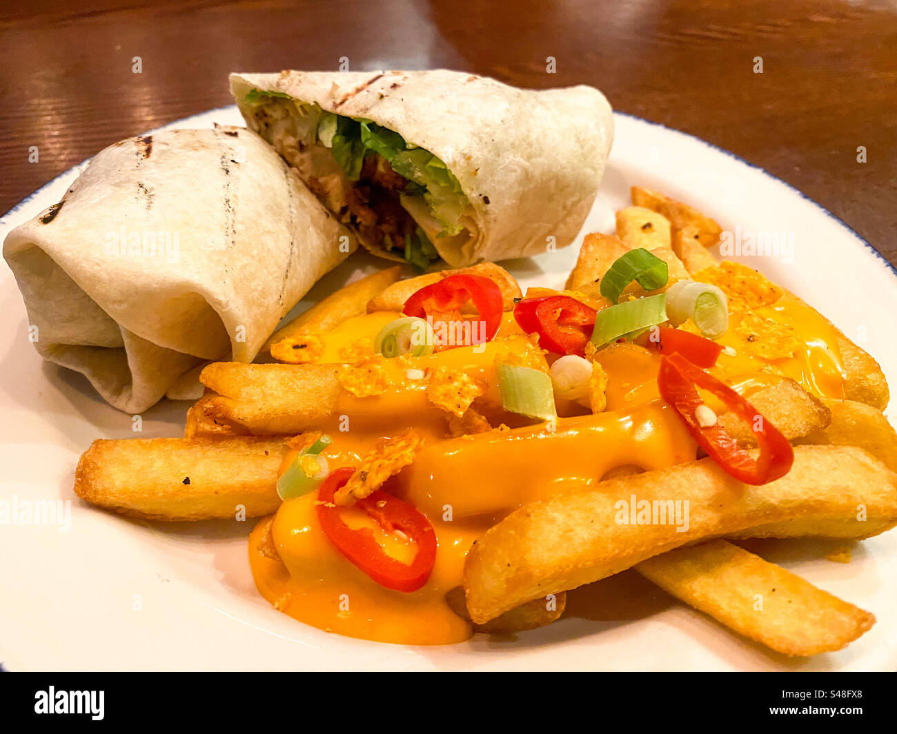 Chicken salad wrap with messy chips for pub lunch Stock Photo - Alamy