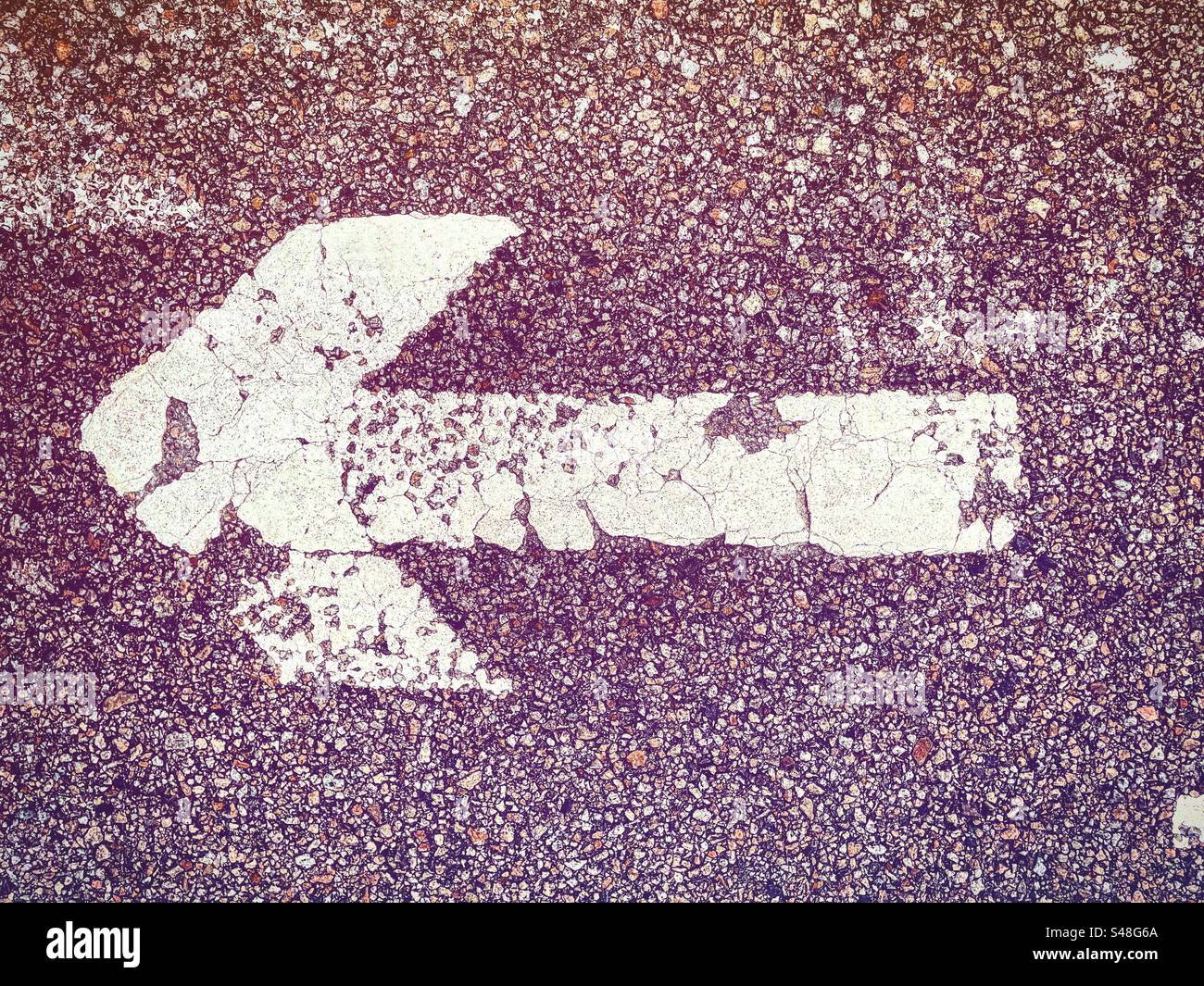 photo of a textured white painted arrow on the ground road pointing ...