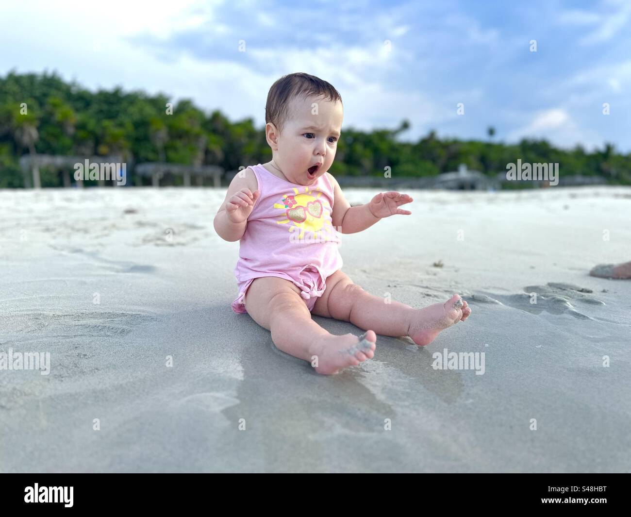 Baby with fascination expression on her face as a wave comes in and the ...