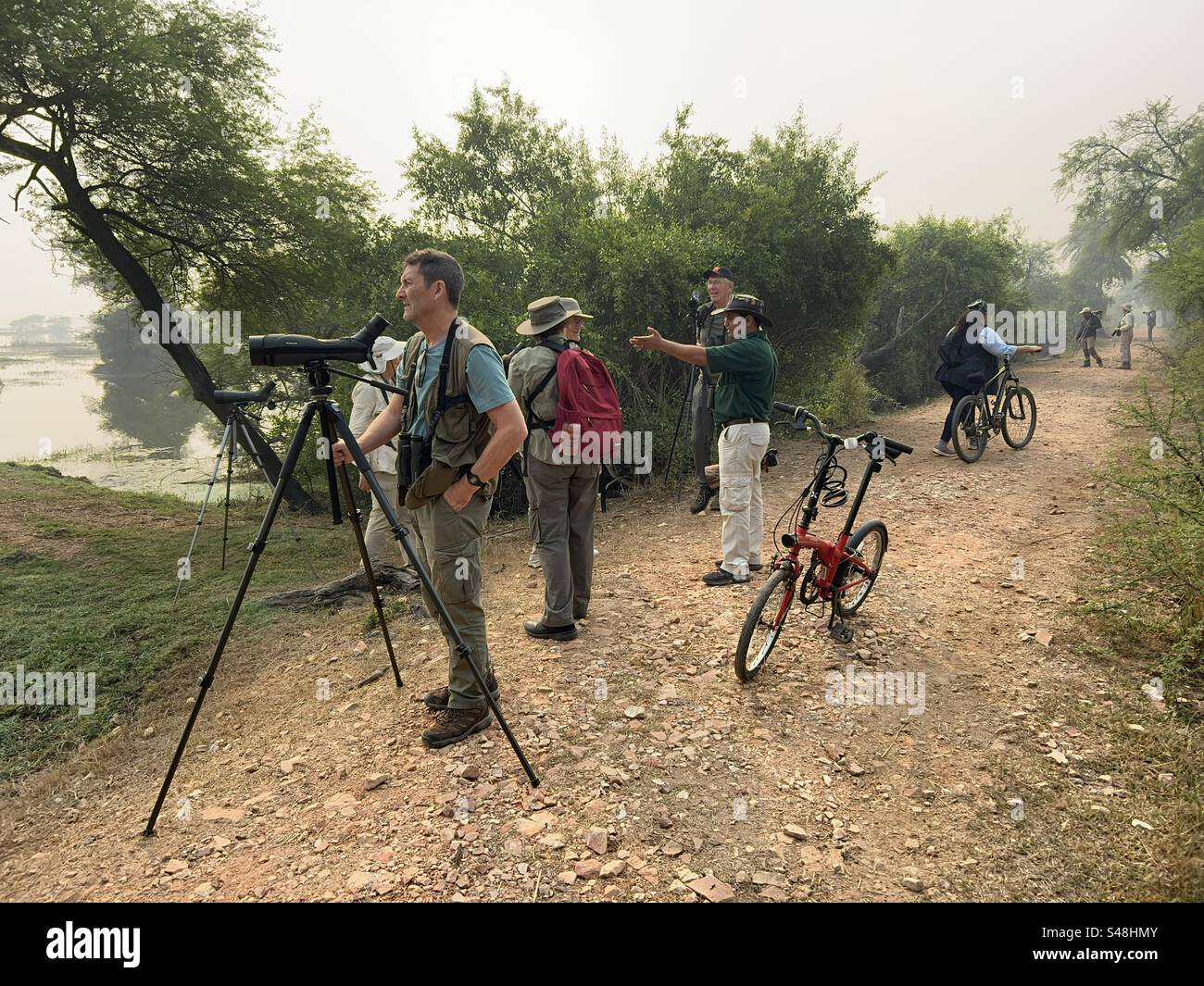 Bird watchers and photographers looking at birds through binoculars and ...