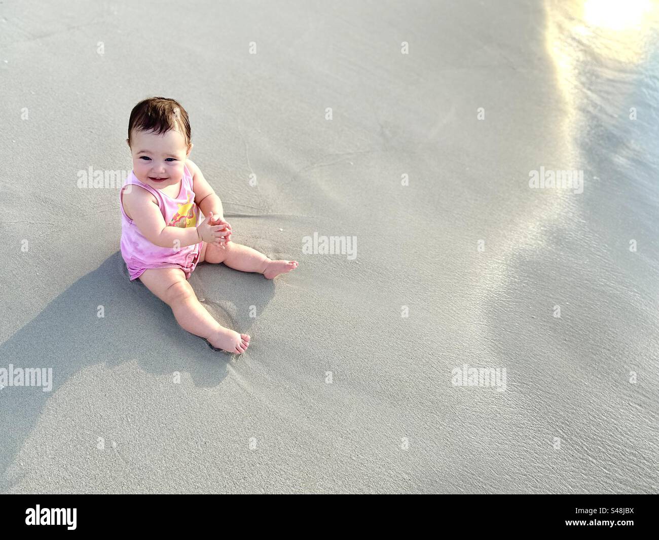 Baby with joy expression clapping at the beach Stock Photo - Alamy