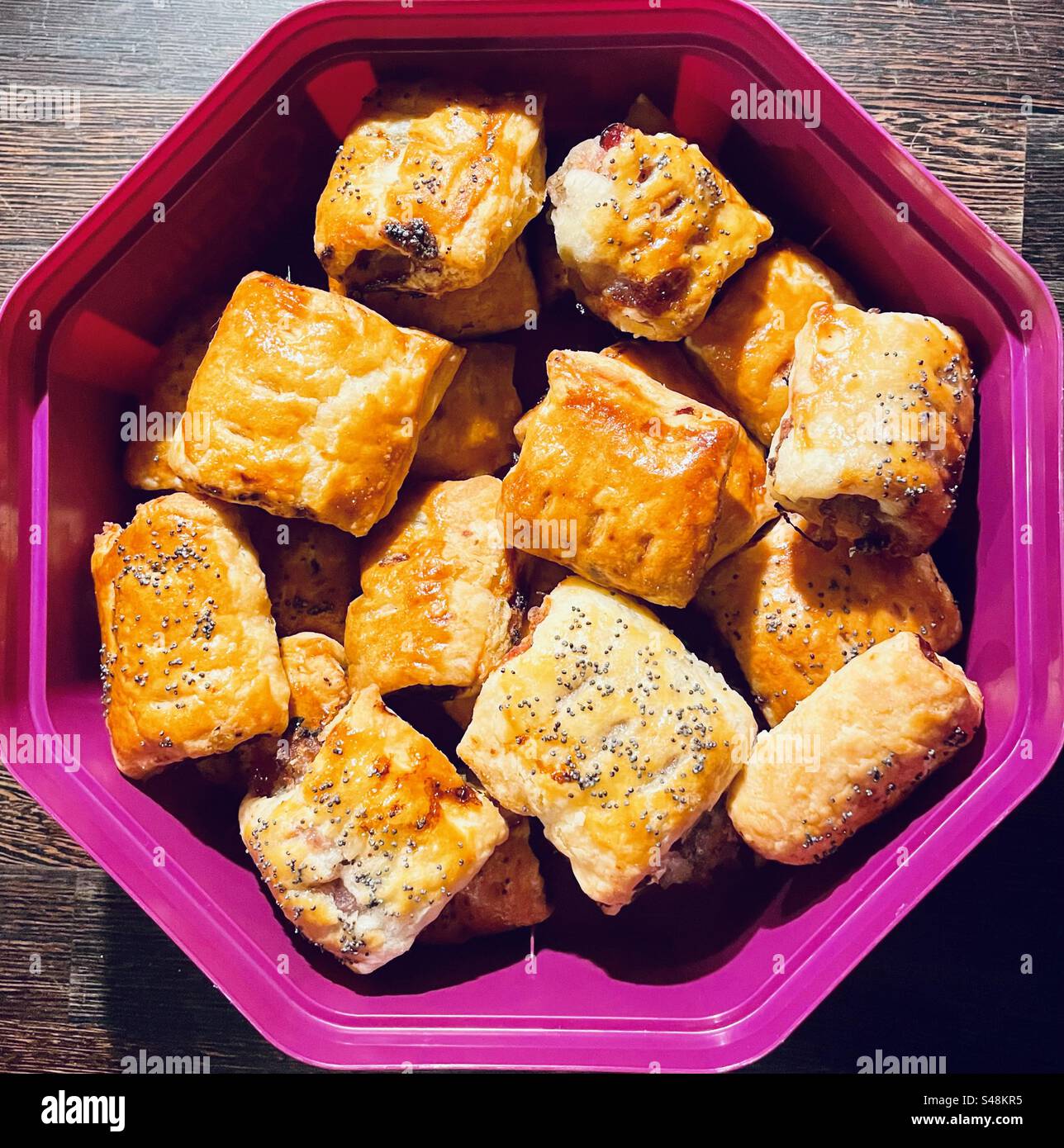 Homemade sausage rolls placed in an empty reused Quality Street plastic ...