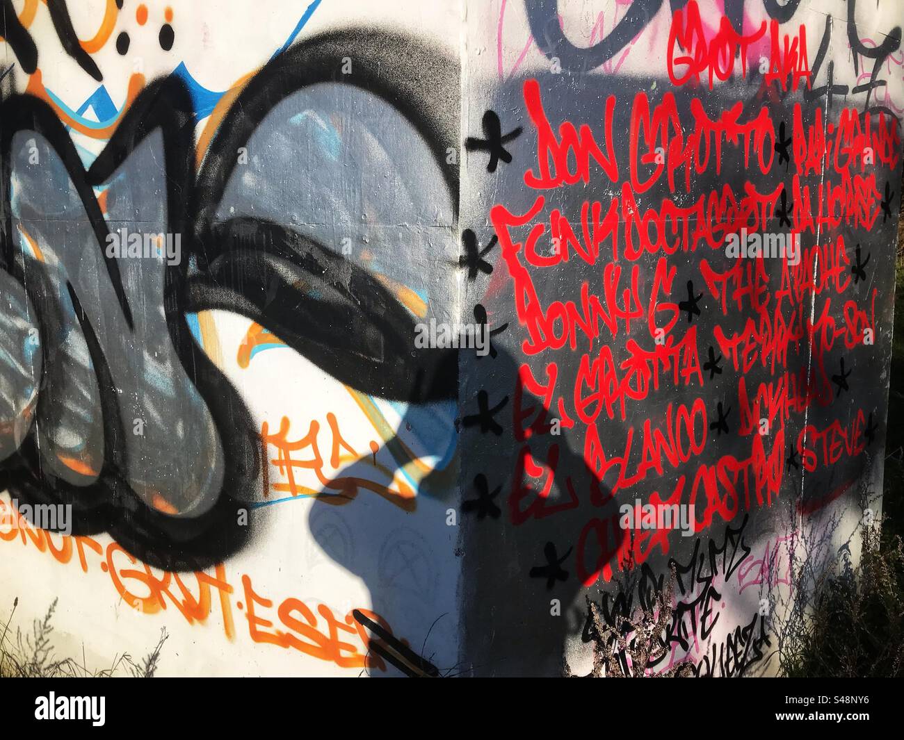 Silhouette of a person taking a photo of urban graffiti art on a street ...