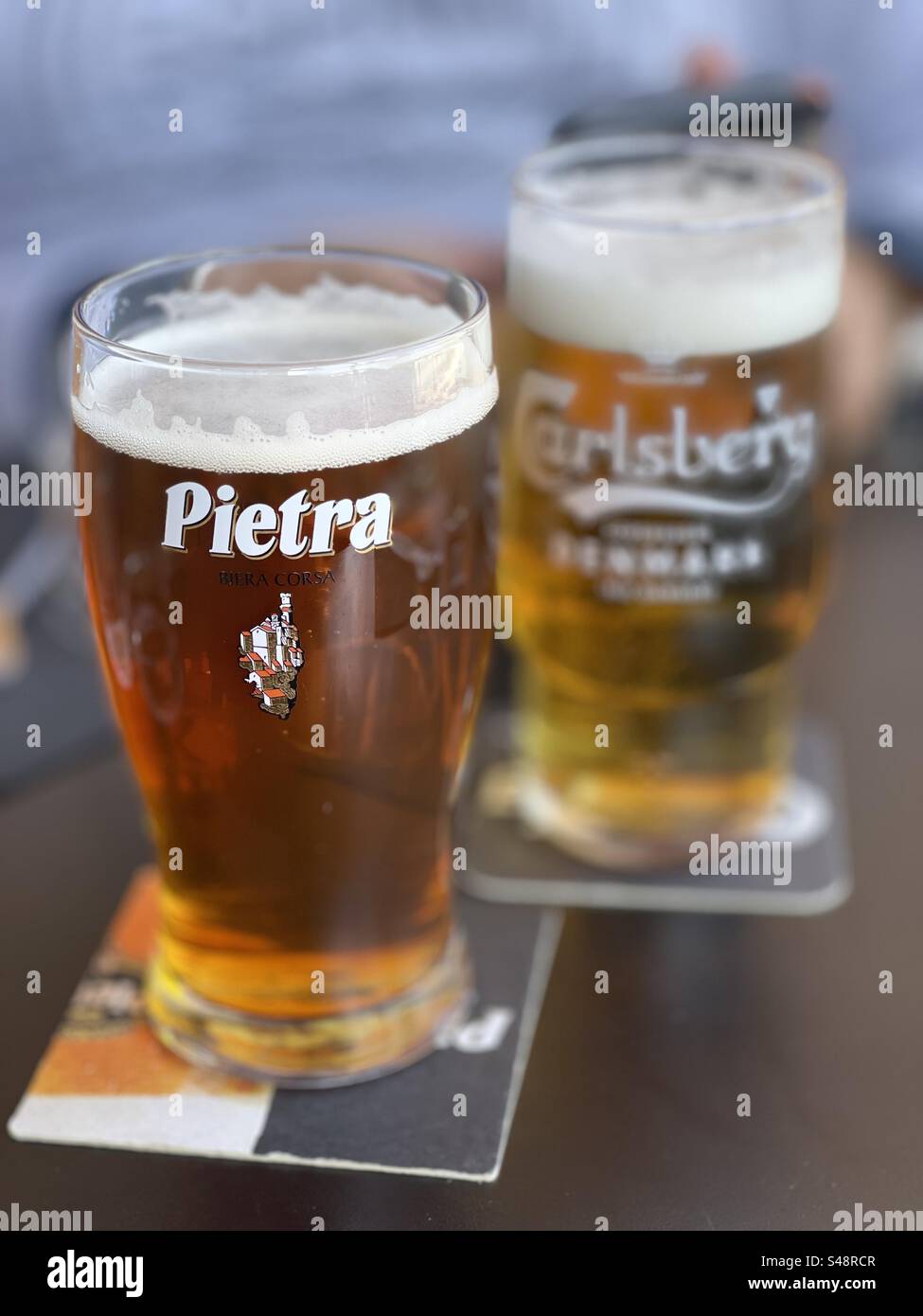 Shot of two glasses of Pietra and Carlsberg beer on a restaurant bar ...