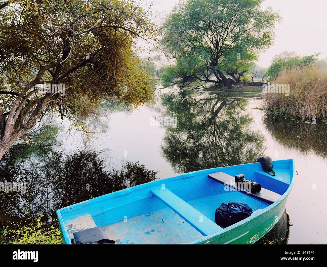 A blue boat with a DSLR camera with telephoto lens and bean bag on a ...
