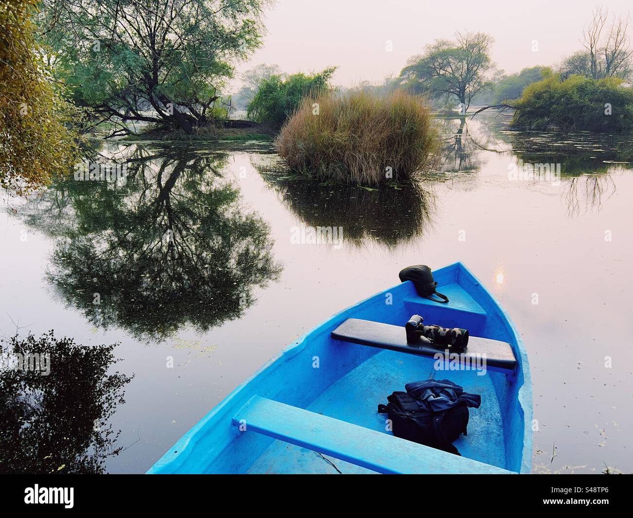 A blue boat with a DSLR camera with telephoto lens and bean bag on a ...