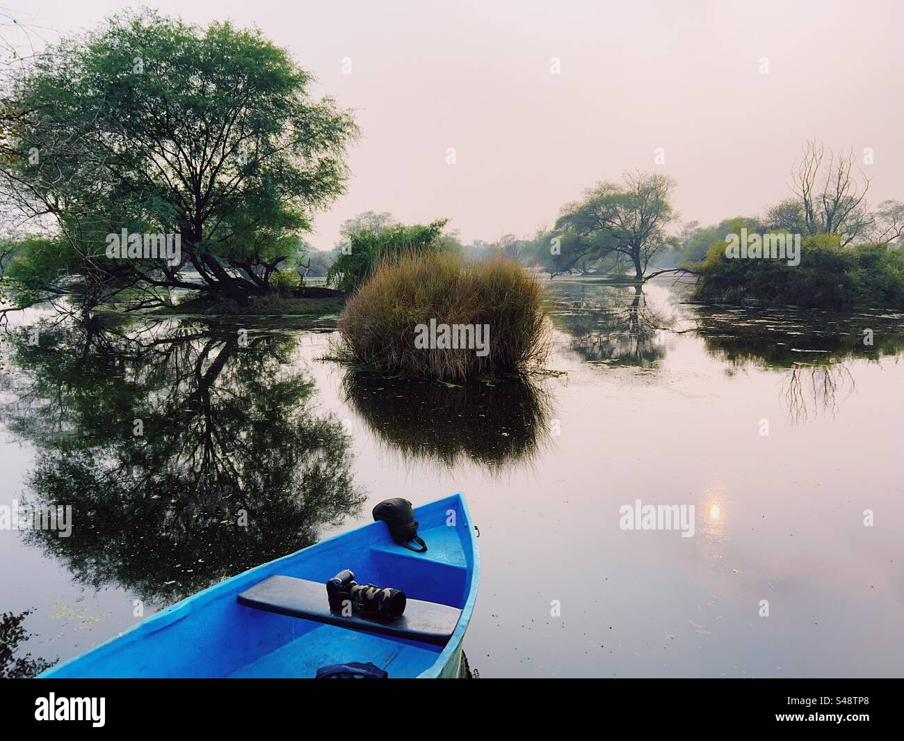 A blue boat with a DSLR camera with telephoto lens and bean bag on a ...