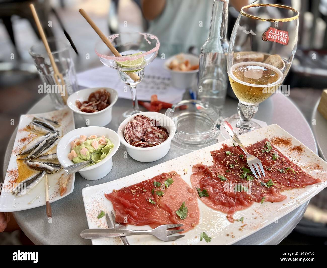 A white bar restaurant table covered with appetizer dishes, tapas and ...