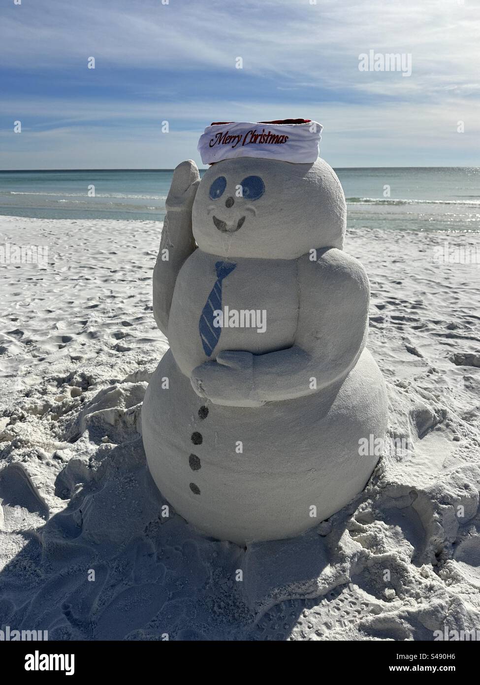 Large snowman sandcastle on the beach with a Merry Christmas hat on ...