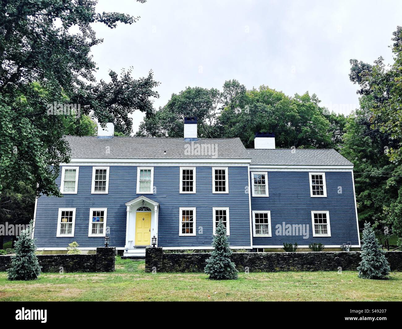 Two-story, colonial house in Madison, Connecticut, USA. Trees and rock ...