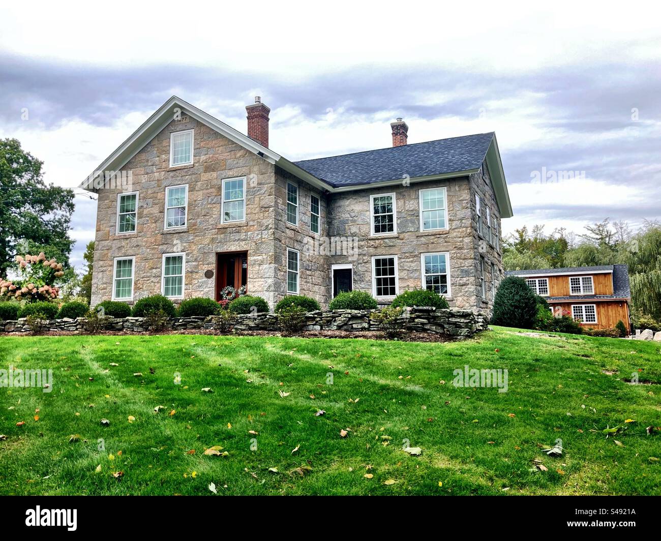 Stone house in Waterford, Connecticut, USA. Low rock wall in front of ...