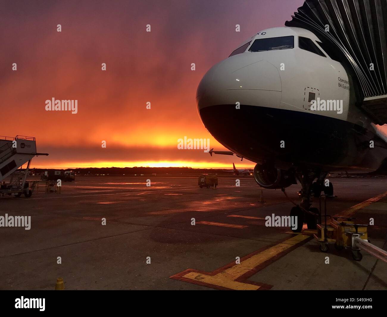 Airplane with airbridge attached during sunrise at Gatwick airport ...