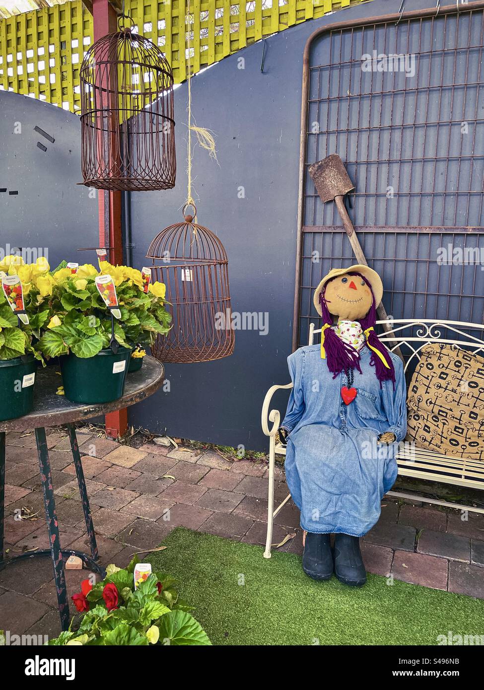 Life-sized Raggedy Ann scarecrow doll sitting on a bench with potted ...