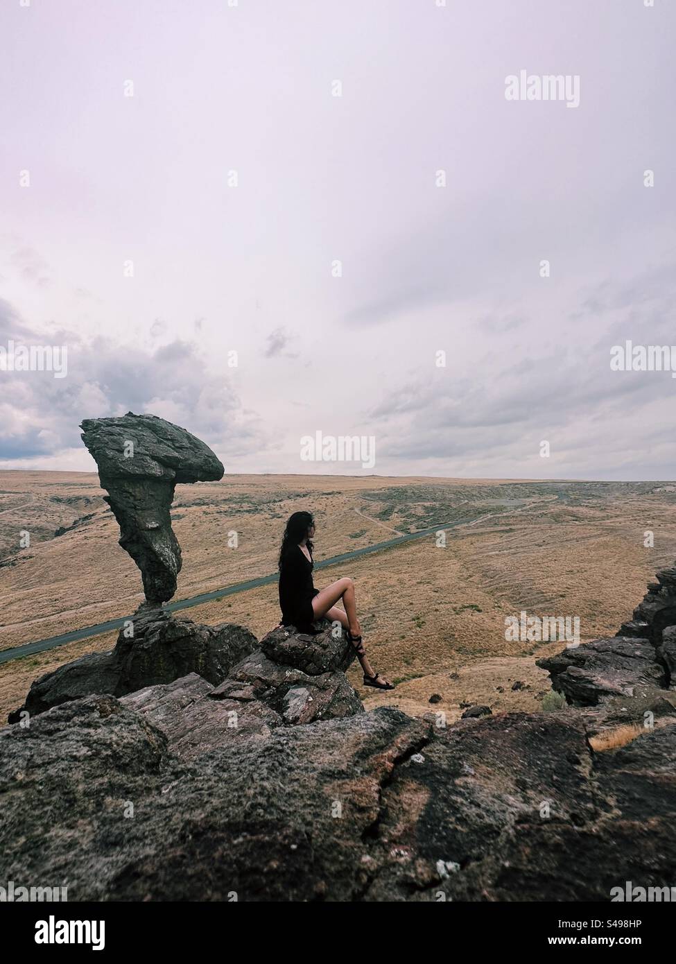 Woman sits on a rock looking parallel to the horizon. A view of ...