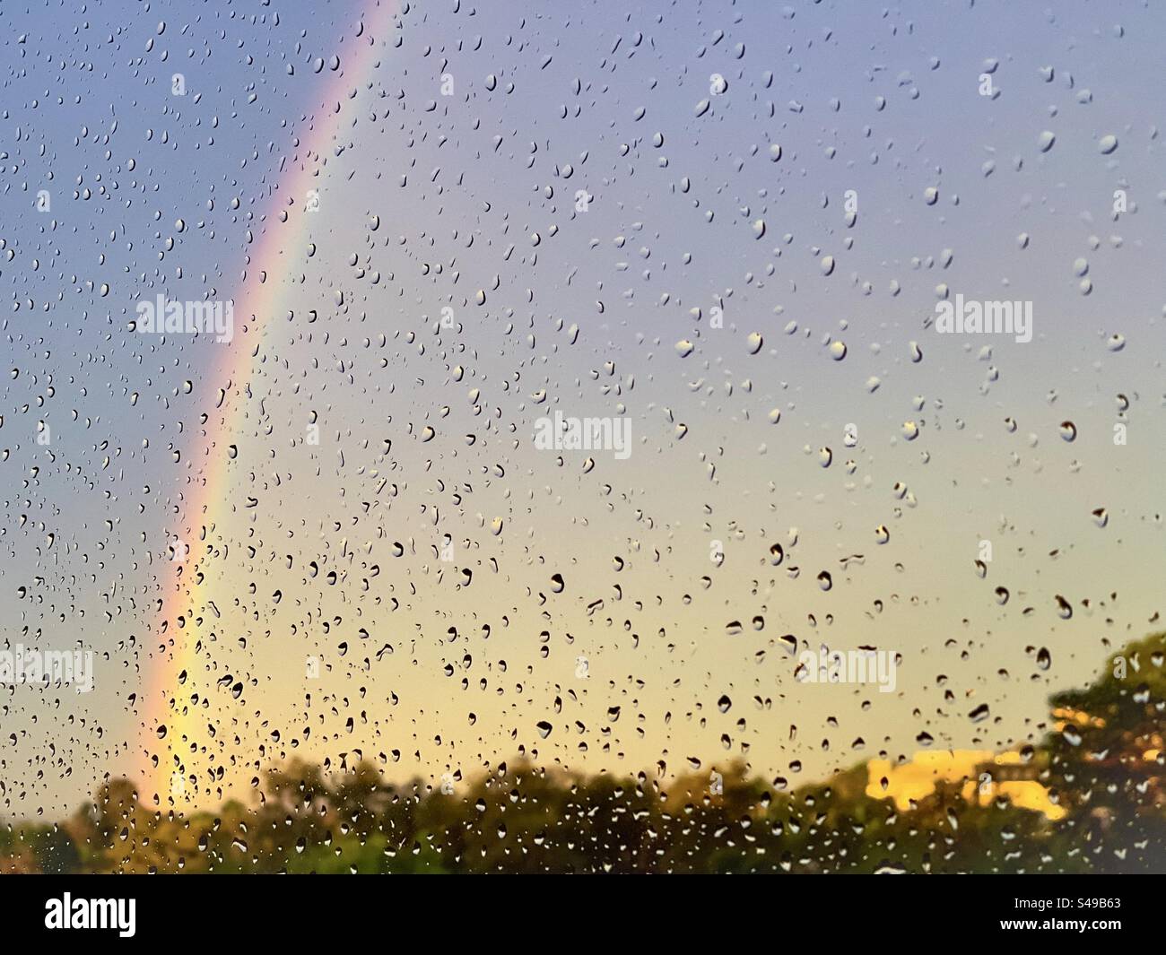 Rainbow in sunset sky seen through raindrops on window Stock Photo - Alamy