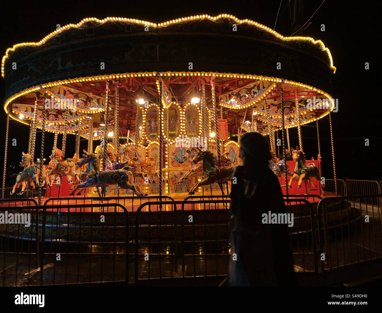 Silhouette of a person passing by a merry go around carousel Stock ...