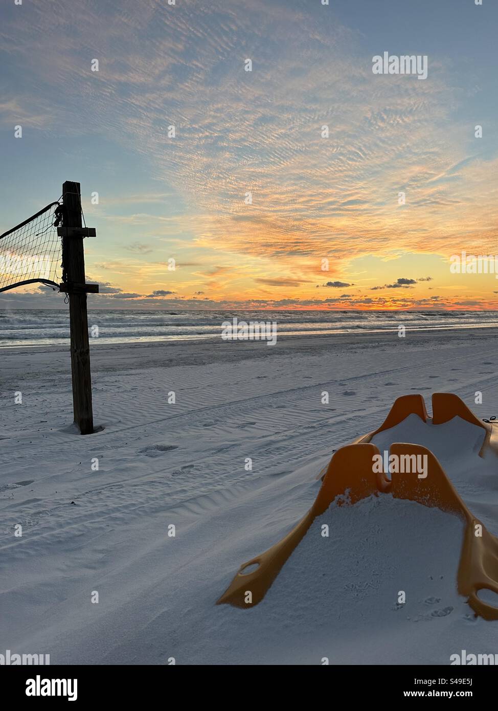 Paddle boat partially covered with white beach sand and sunset sky ...