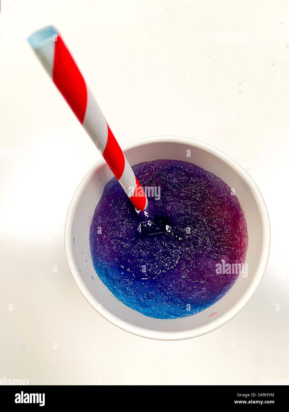 Top down view of a slushie with a red and white striped drinking straw ...