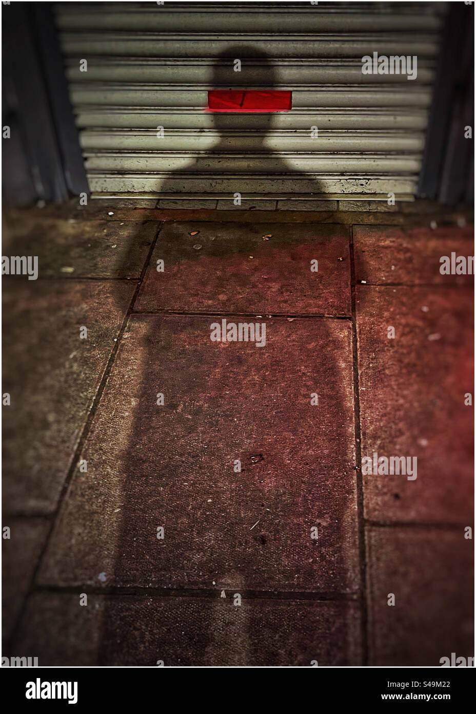 Figure casts shadow across pavement and onto metal shutters Stock Photo ...