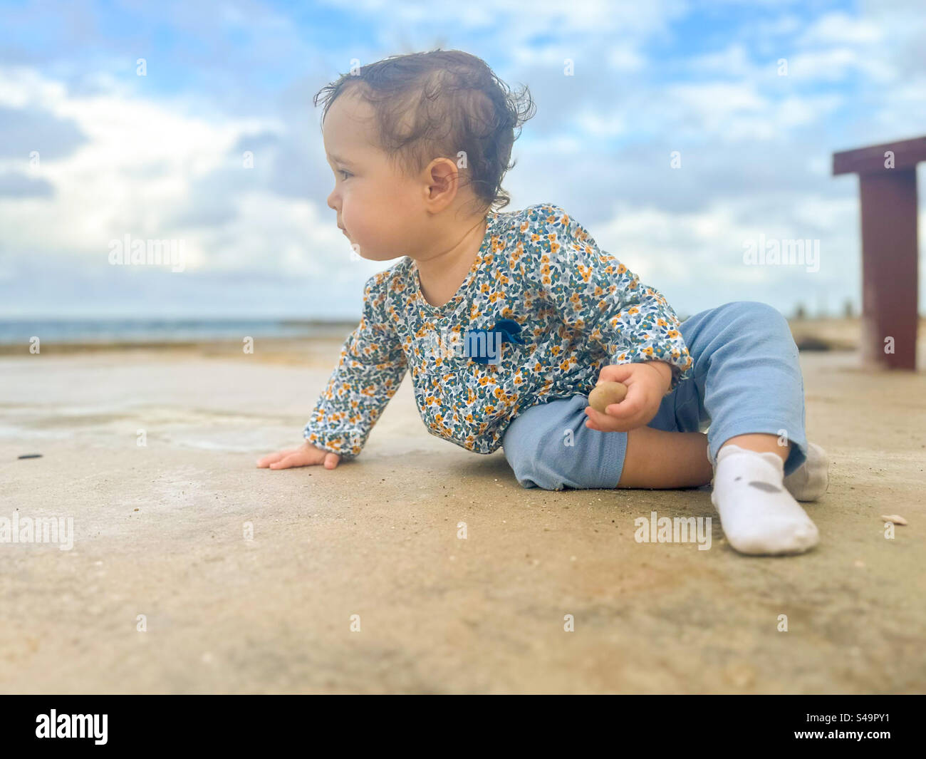 Toddler in the ocean looking out to sea holding a pebble Stock Photo ...