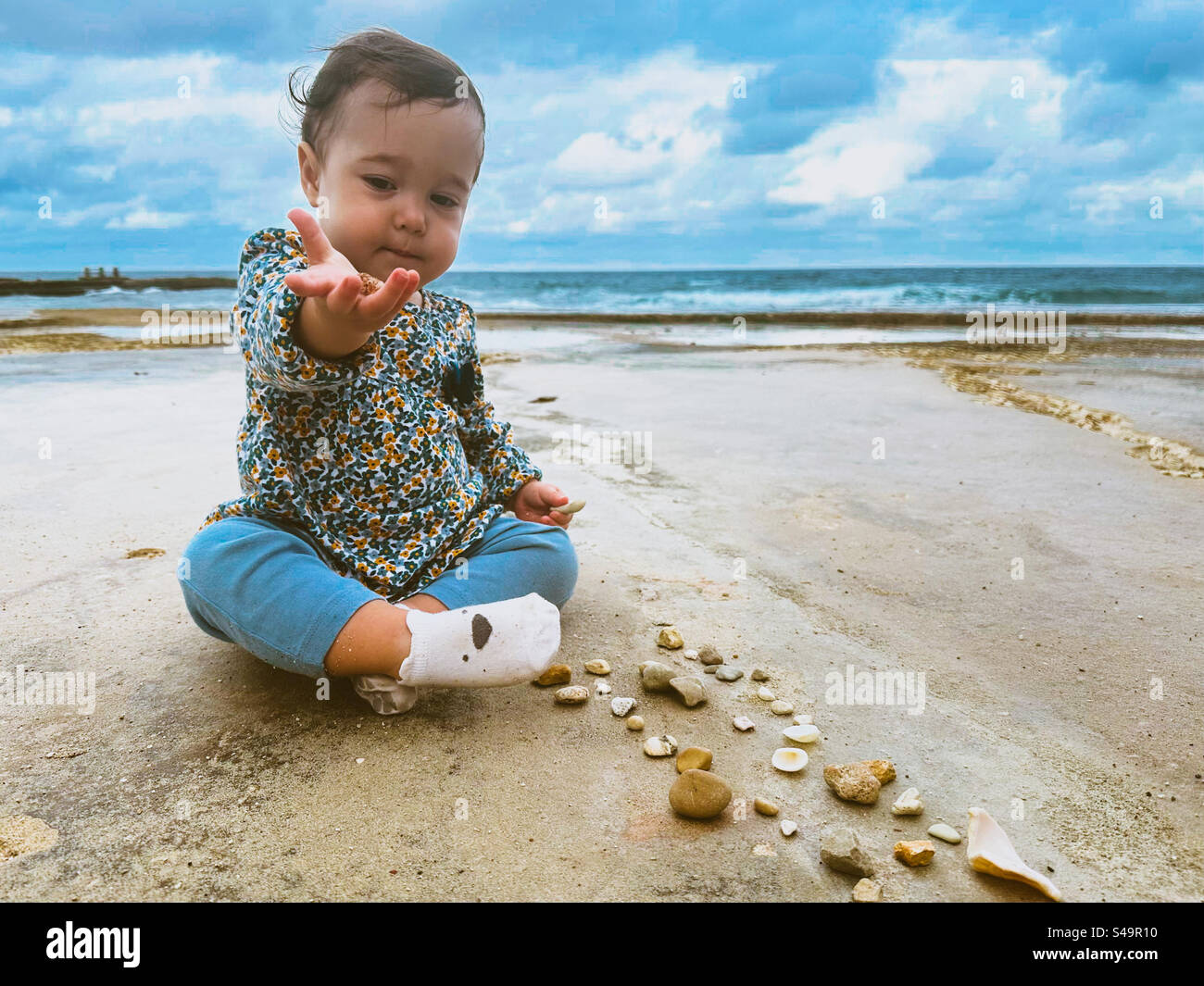 Toddler playing with pebbles in the coast Stock Photo - Alamy