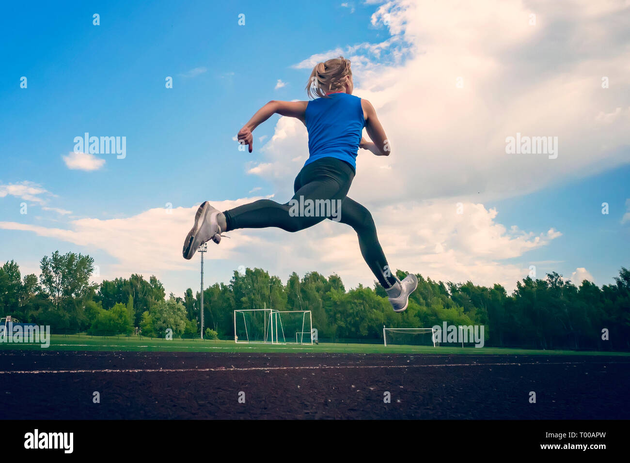 young fitness woman runner running on stadium track. The time of the ...