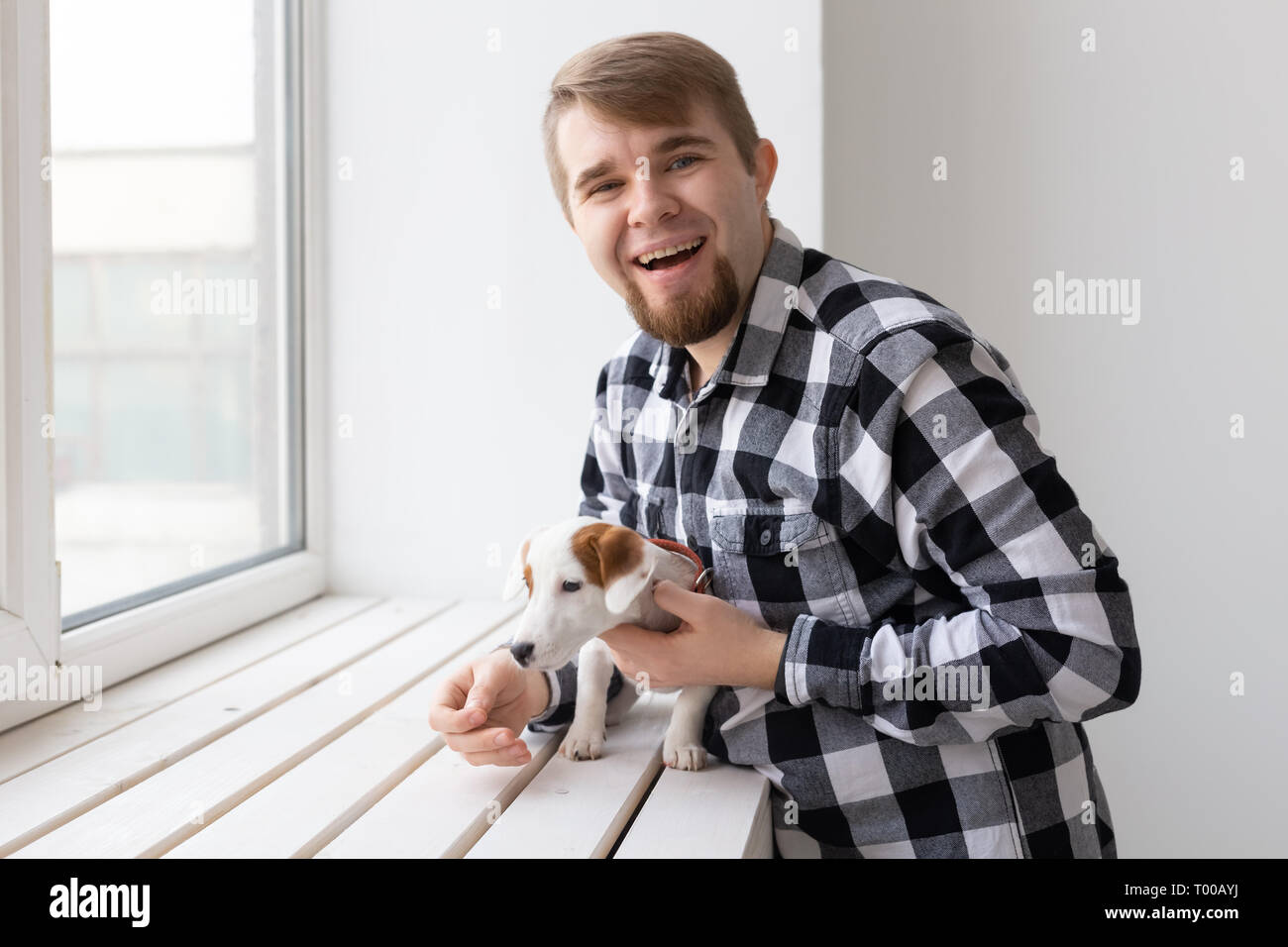 people, pets and animals concept - young man hugging jack russell ...