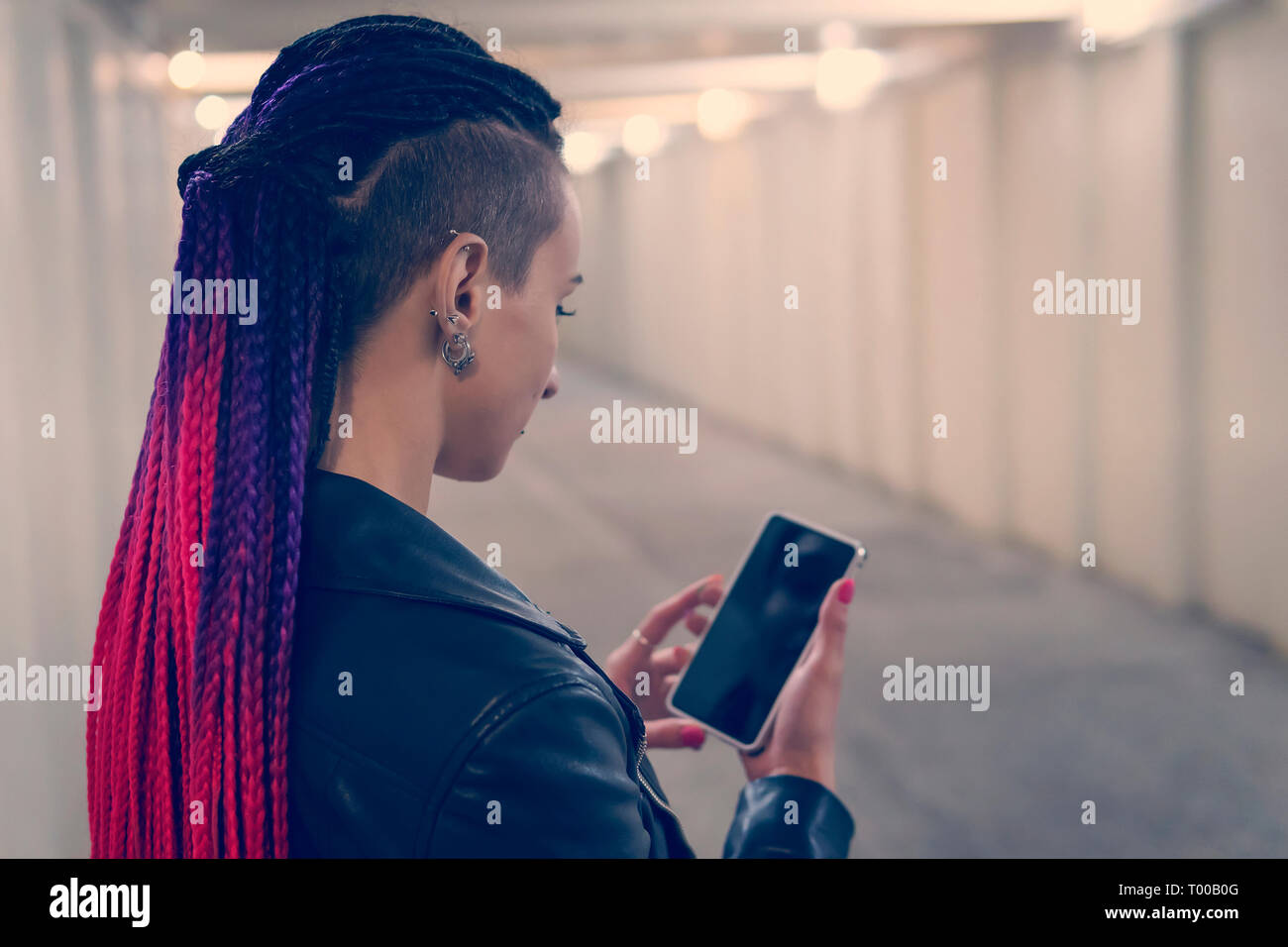 young woman with mobile phone on the street. Punk girl with a informal ...