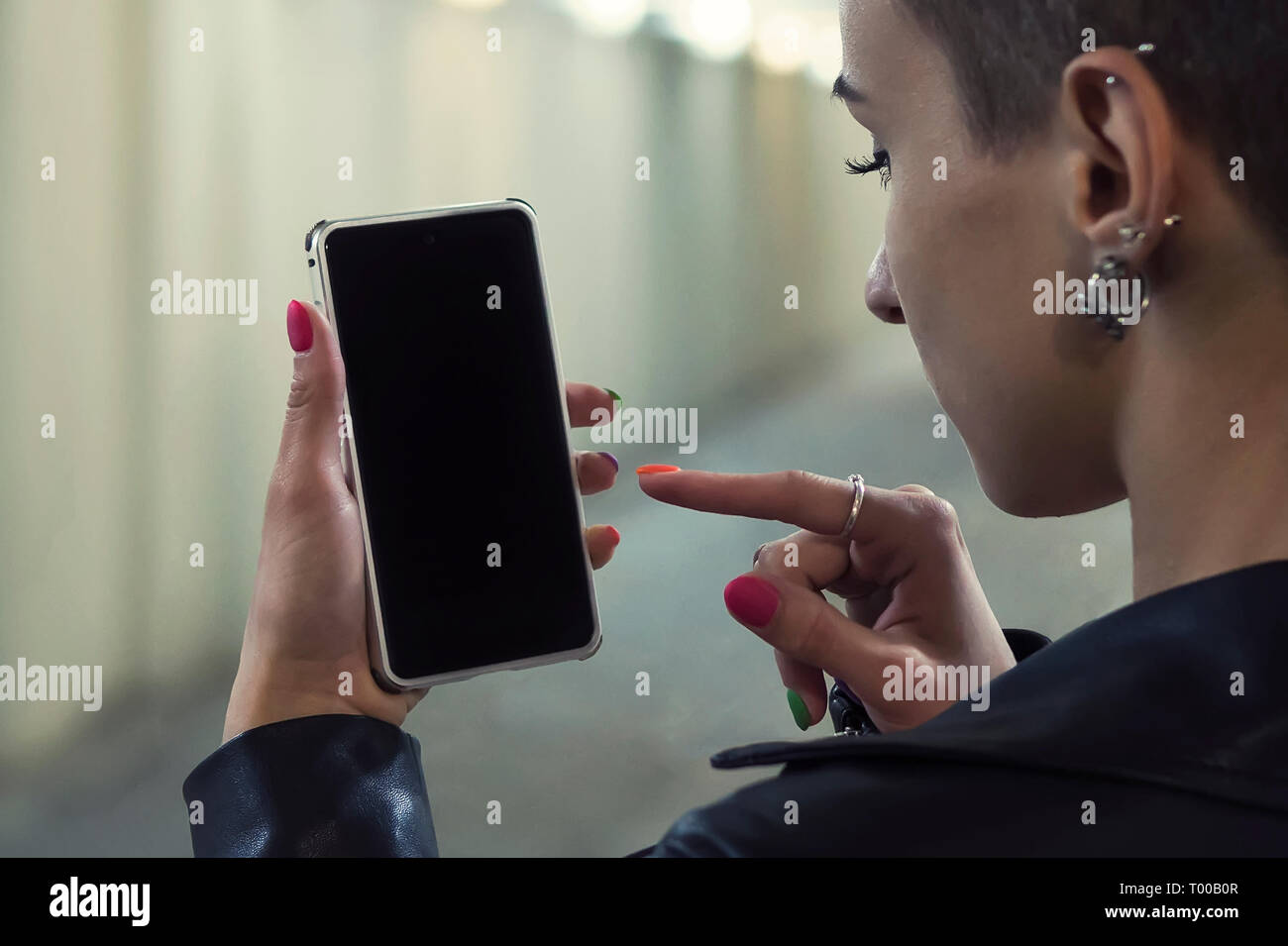 young woman with mobile phone on the street. Punk girl with a informal ...