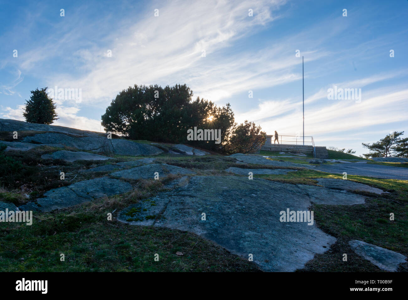Man standing on top of ramberget hill with sunrays peeping through bush ...