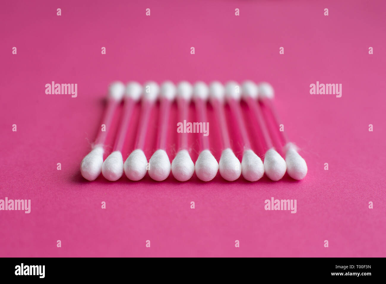 Closeup side view on cotton buds laid in a horizontal line on pink ...