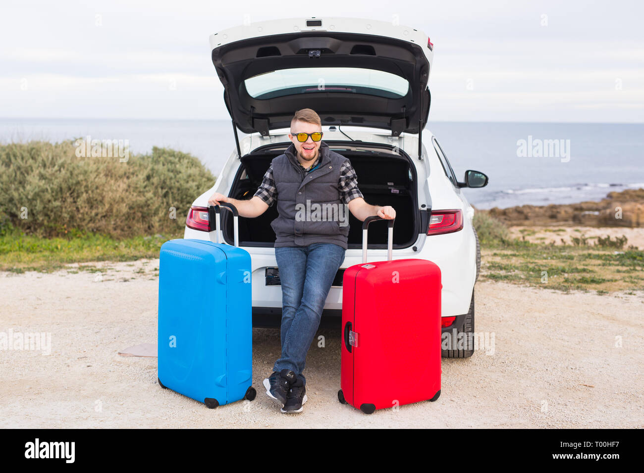 Man sitting on back of car smiling. Summer road trip Stock Photo - Alamy