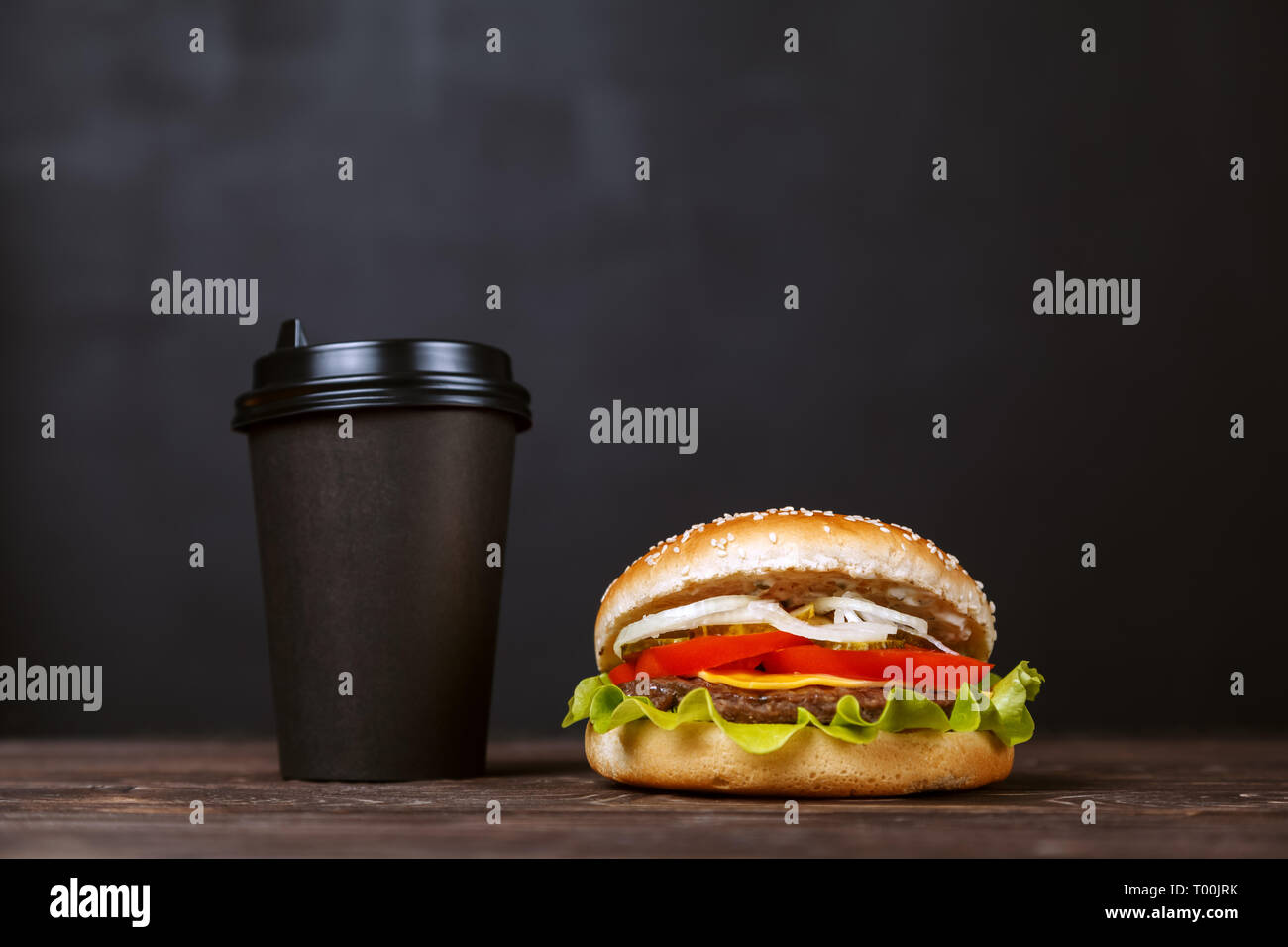 Beef Burger with bacon and coffee in a black paper Cup on a wooden ...