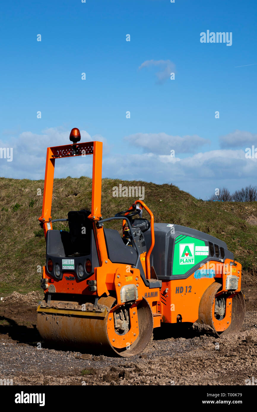 construction site roller parked on grass area adjacent to building site ...