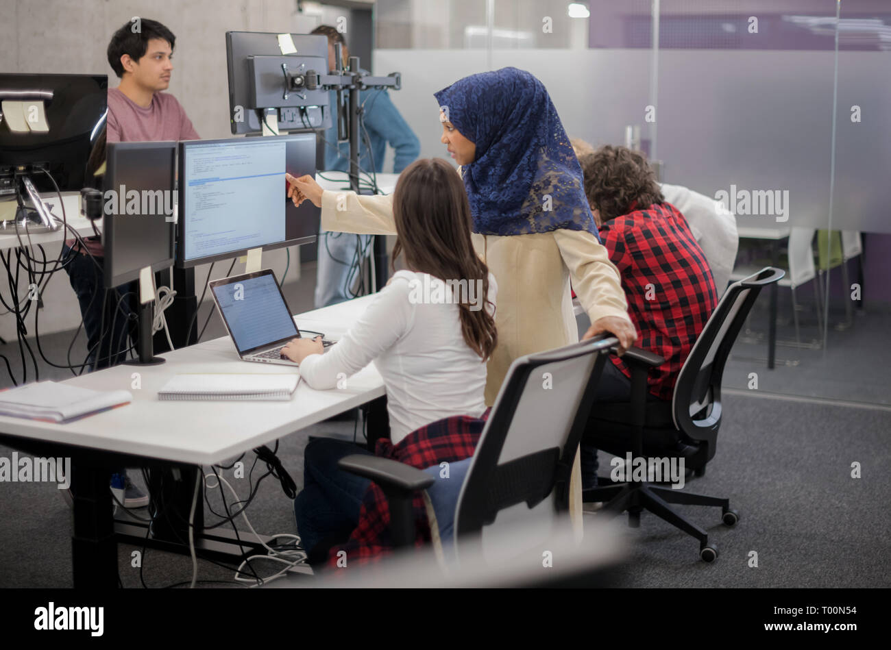 young multiethnics business team of software developers working together using laptop computer ...