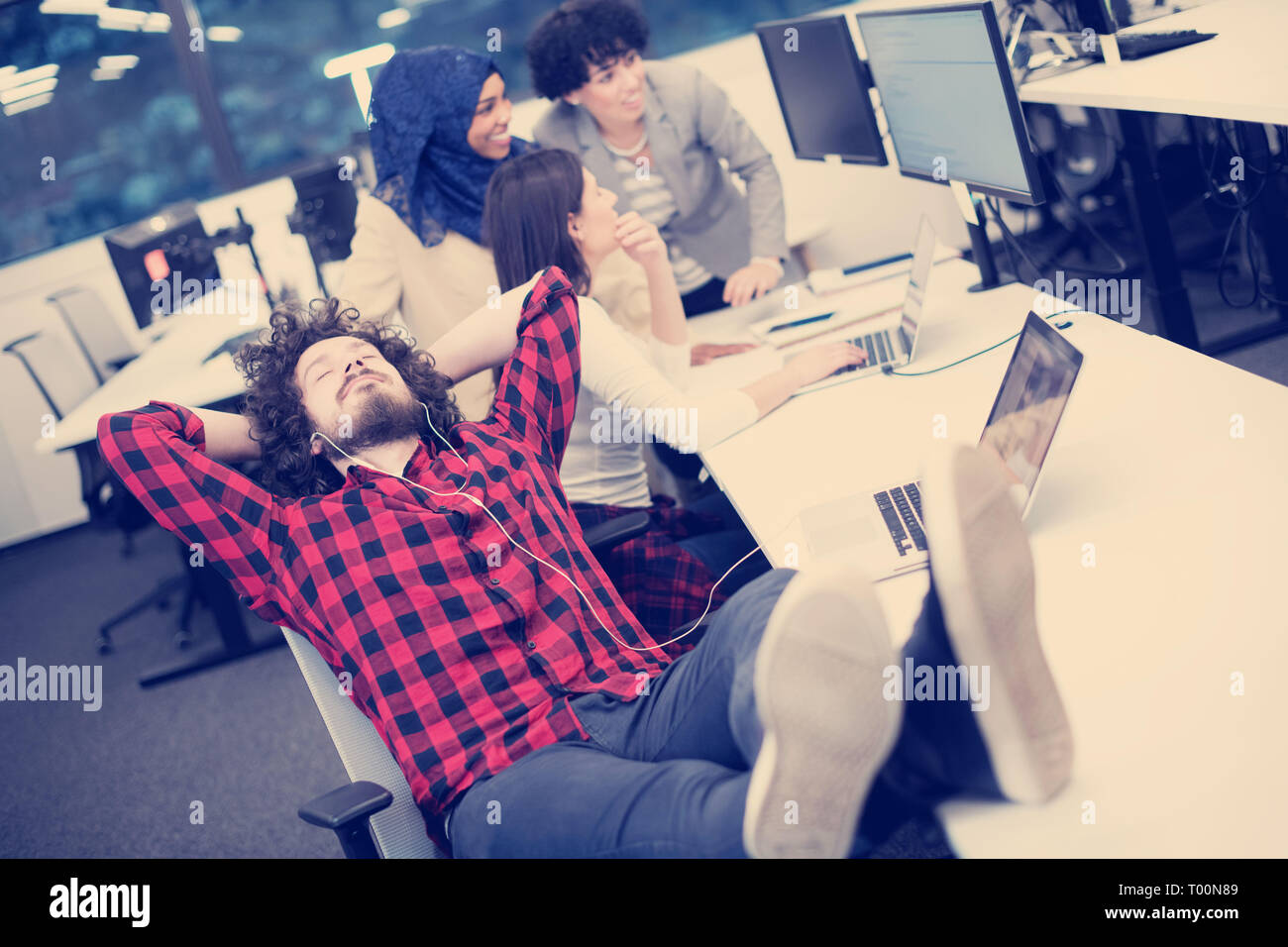 young software developer resting with legs on desk while his ...