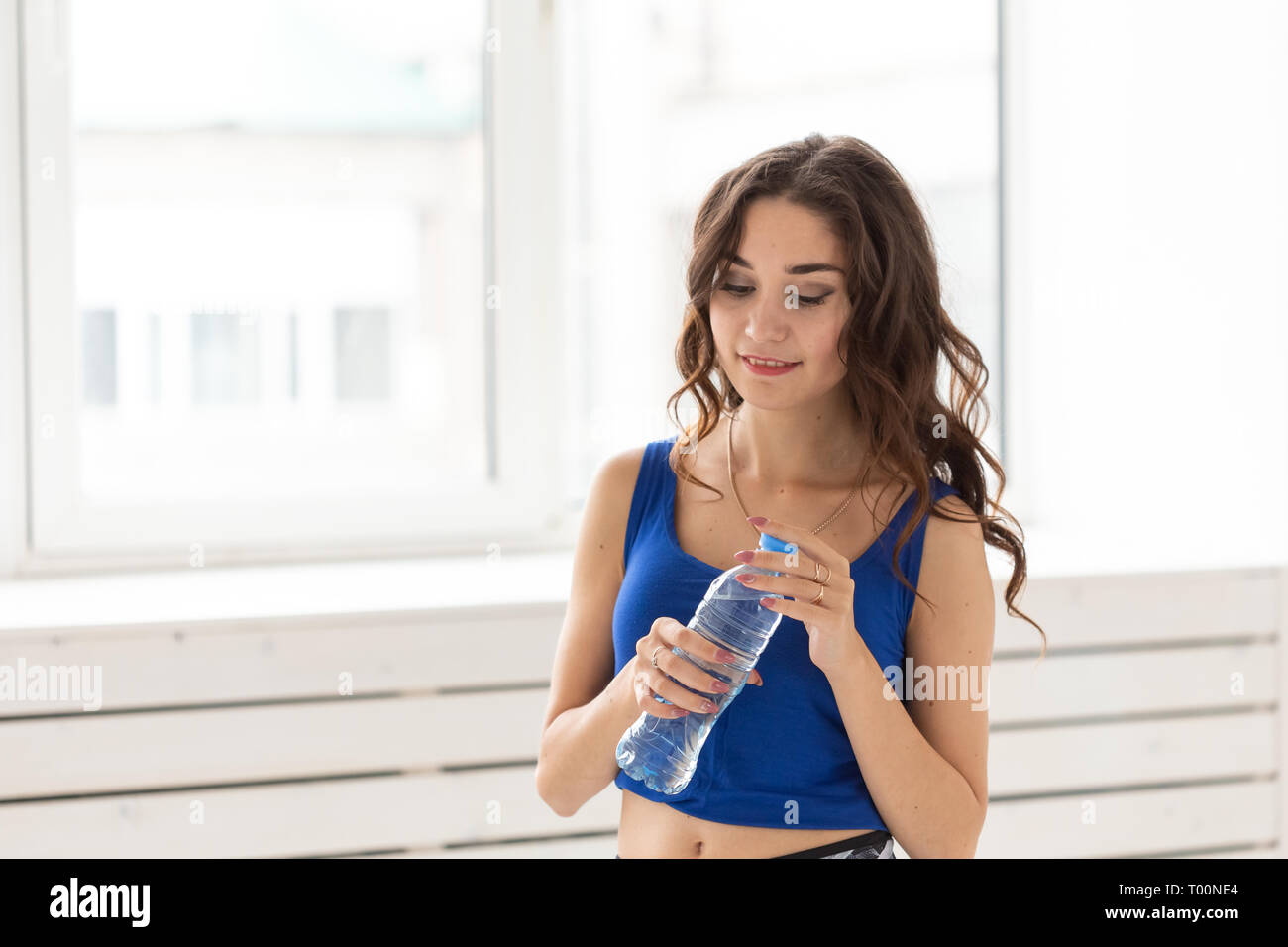 Sport, healthy lifestyle, people concept - young woman drinking water ...