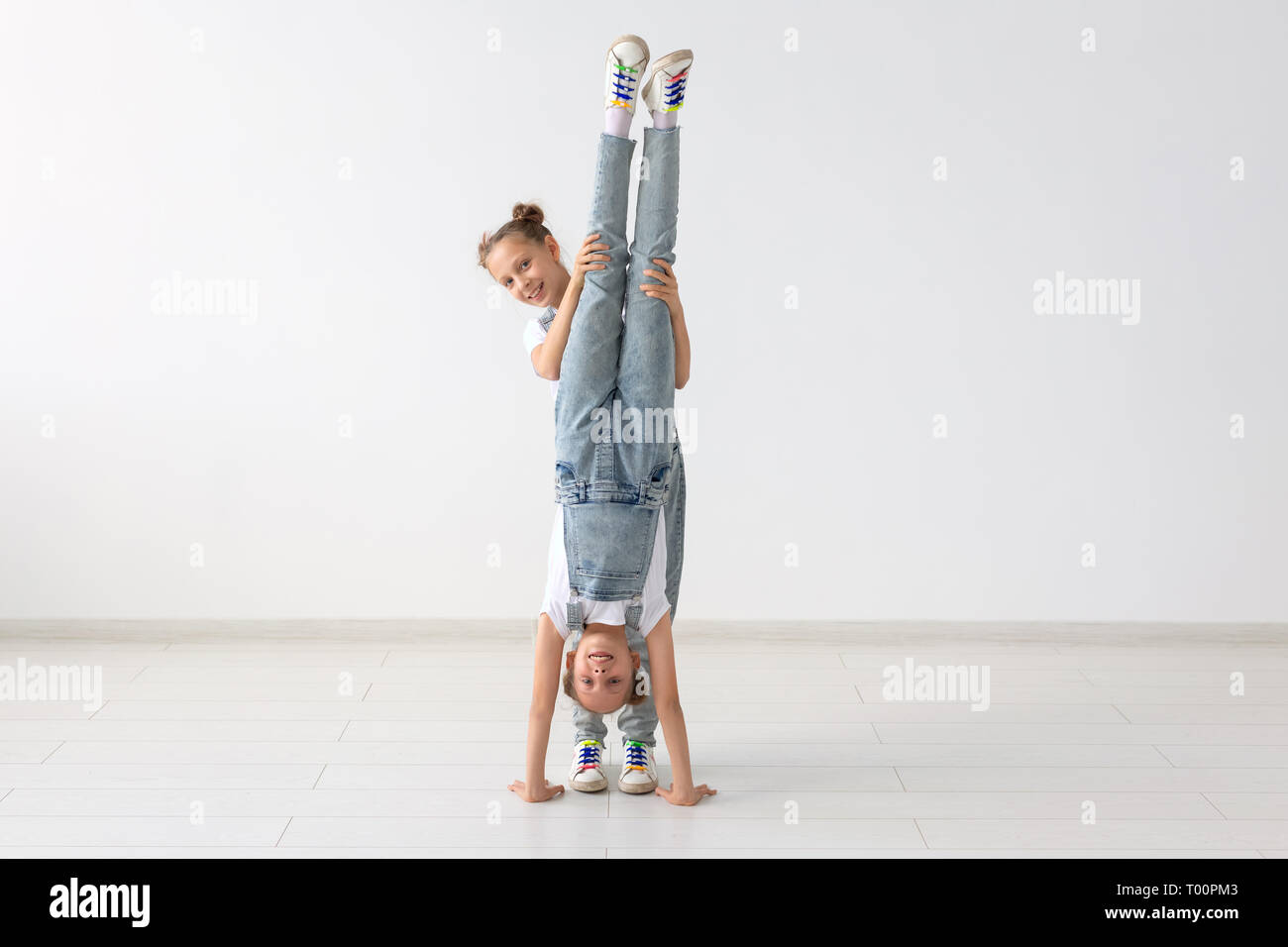 Family and sport concept - Two acrobat twin girls are standing on the ...