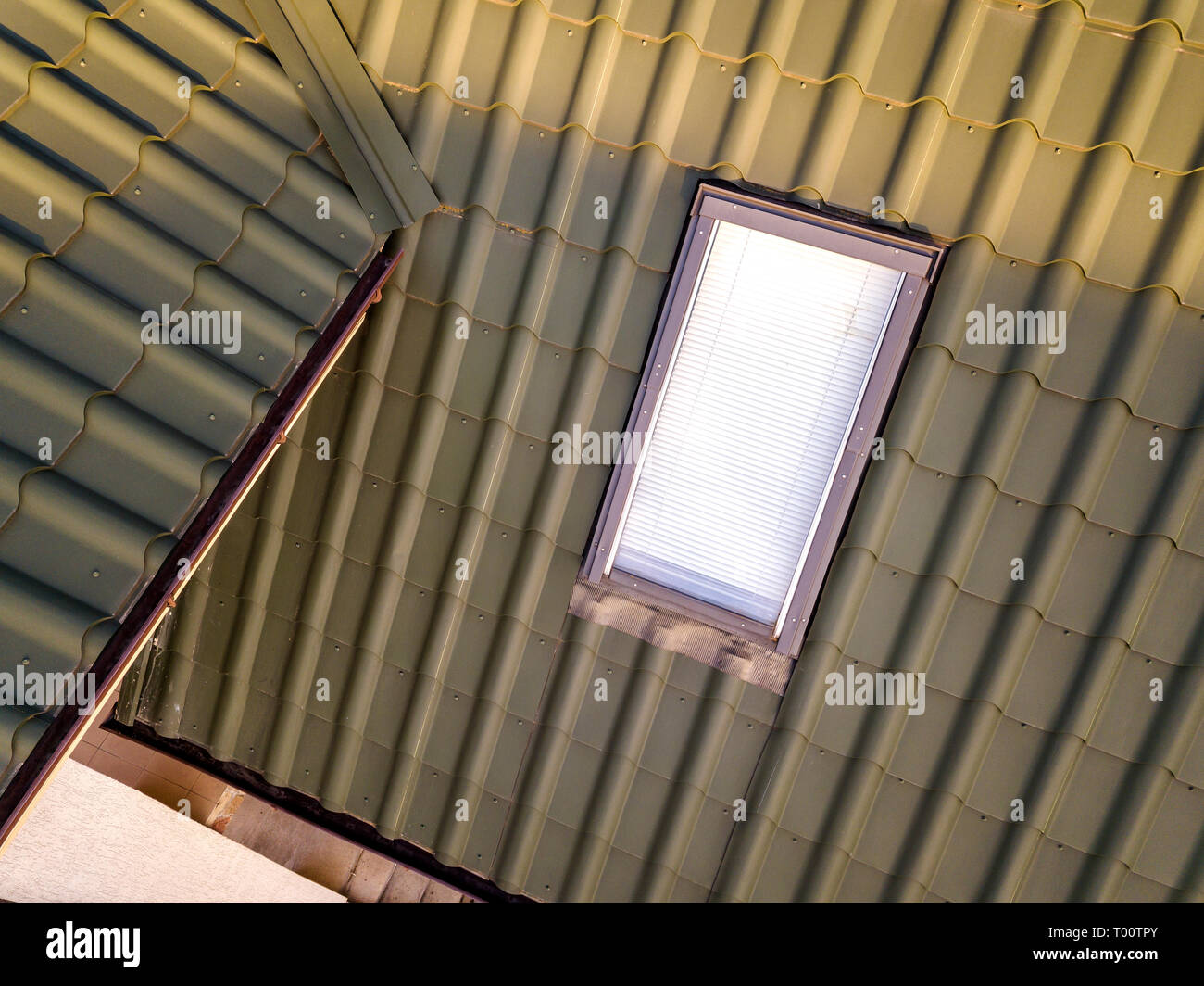 Close-up of new attic plastic window installed in shingled house roof ...