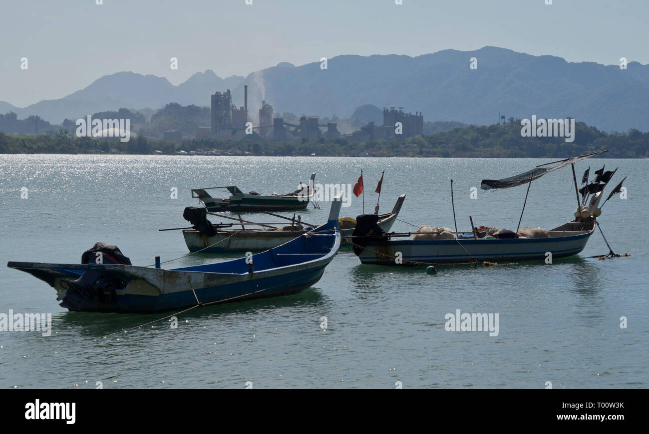 Fishing boats on a beach with cement factory in background in the ...
