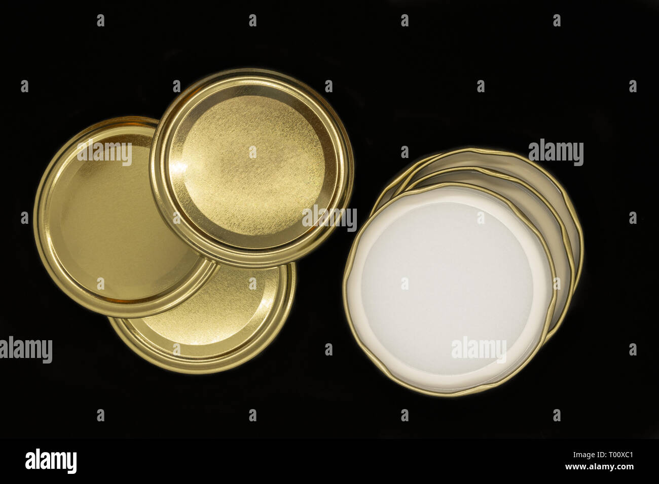 Golden jar lids isolated on black background Stock Photo - Alamy
