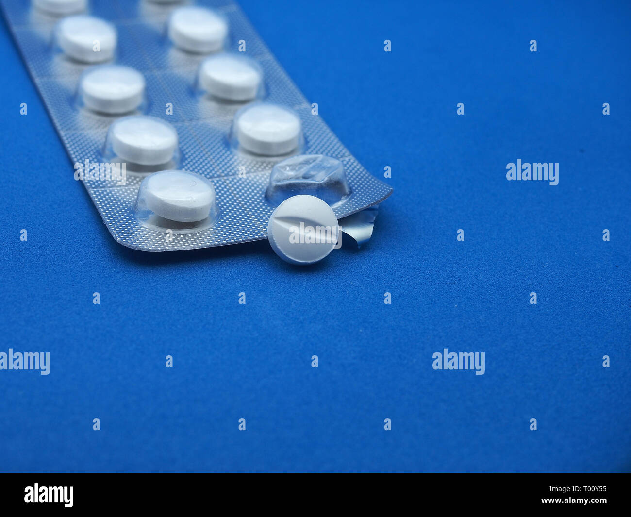 White tablets on a blue background. One tablet without packaging, the ...