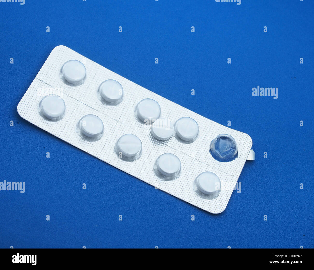 White tablets on a blue background. One tablet without packaging, the ...
