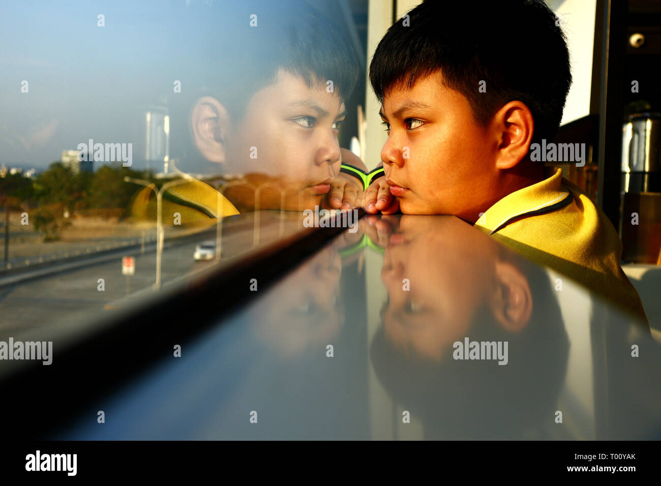 Photo of a young Asian boy looking out a glass window Stock Photo - Alamy