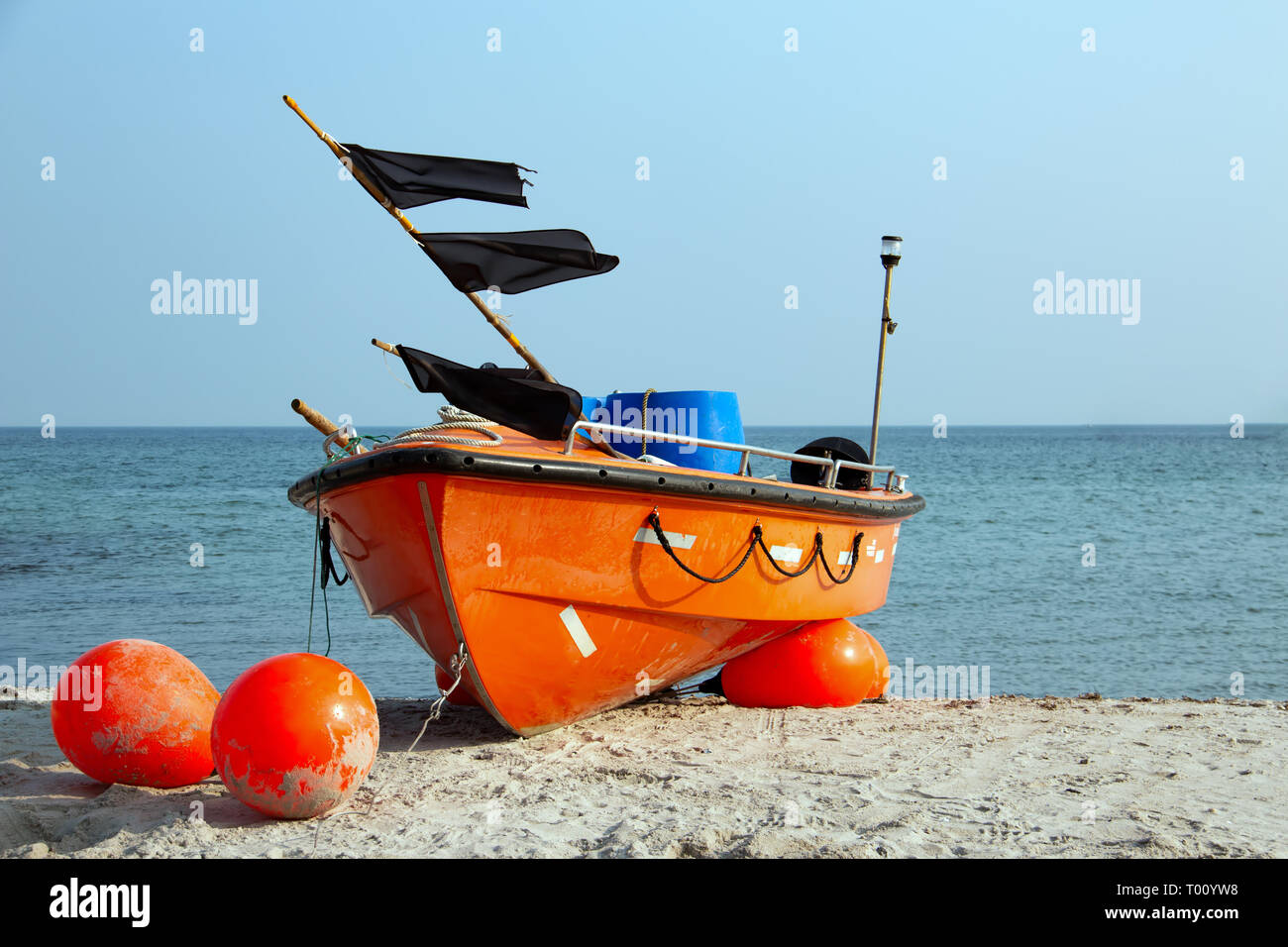 Orange fishing boat with black flags on the beach Stock Photo - Alamy