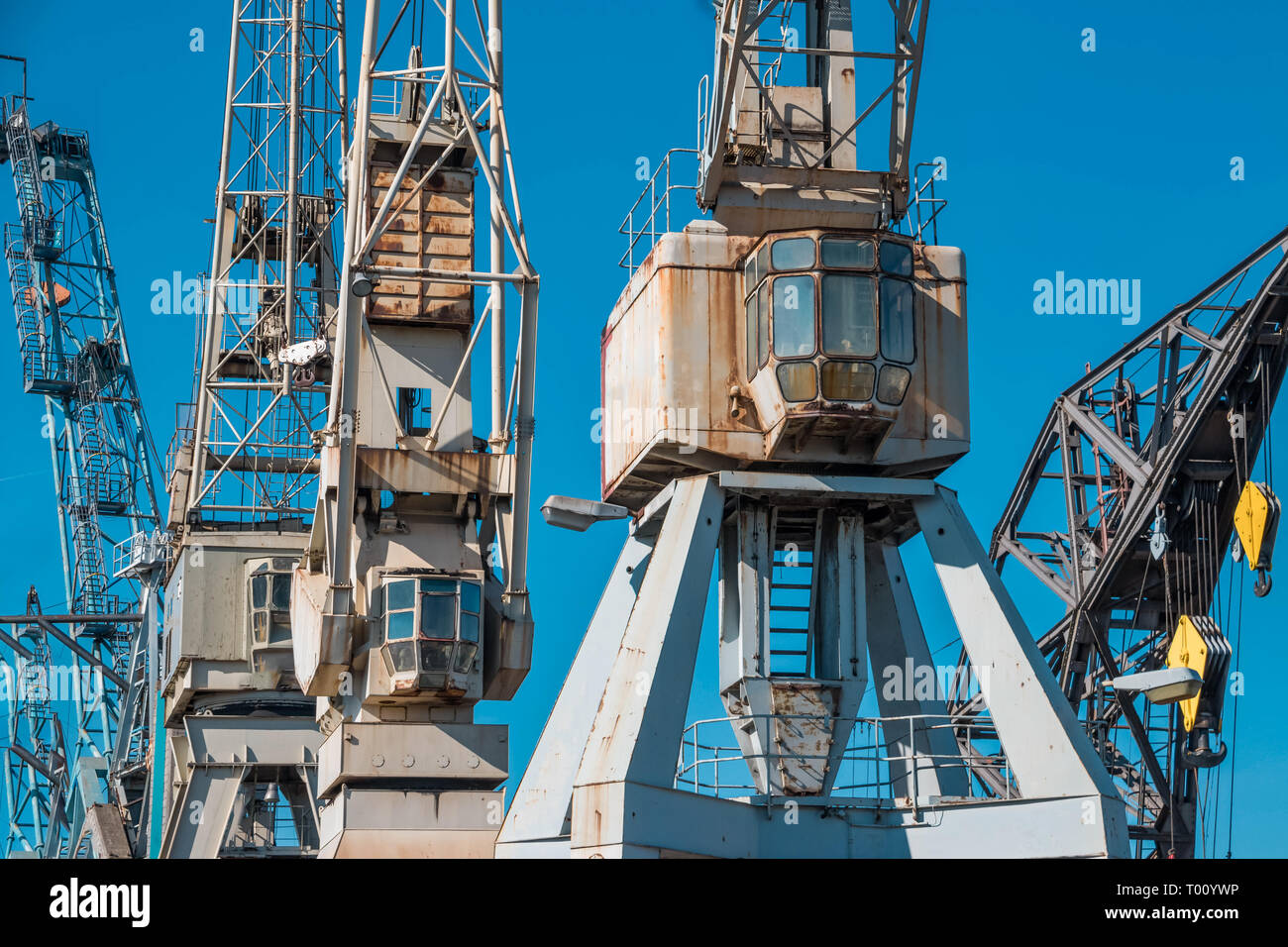 Old, rusty harbor cranes with blue sky Stock Photo - Alamy
