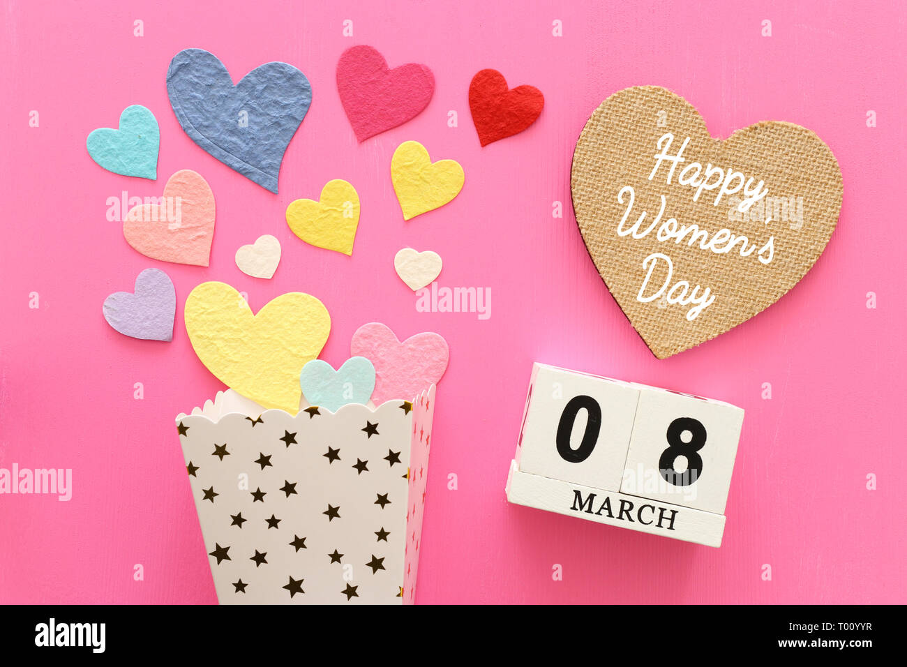 wooden March 8 calendar next to paper colorful hearts over pink wooden ...