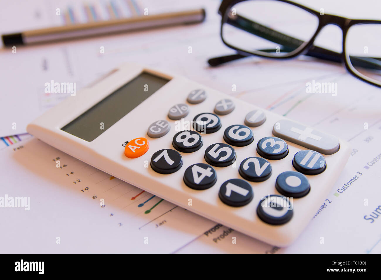 data analyzing with calculator, notebook and pen. on charts and graph ...